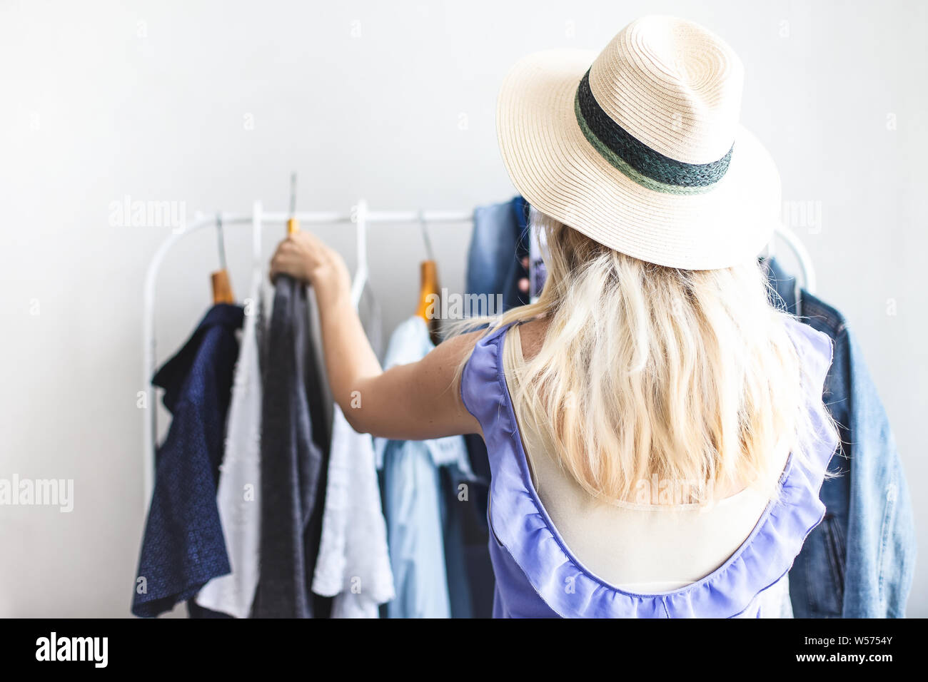 Blondy girl near a wardrobe with clothes can not choose what to wear ...