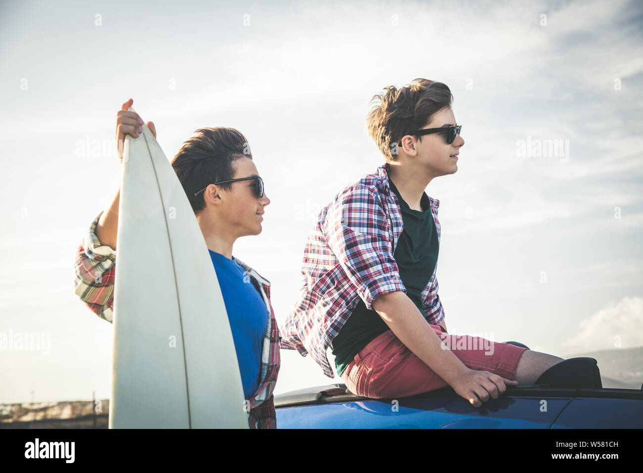 Two young happy teenager best friends smiling with surf board. Profile ...
