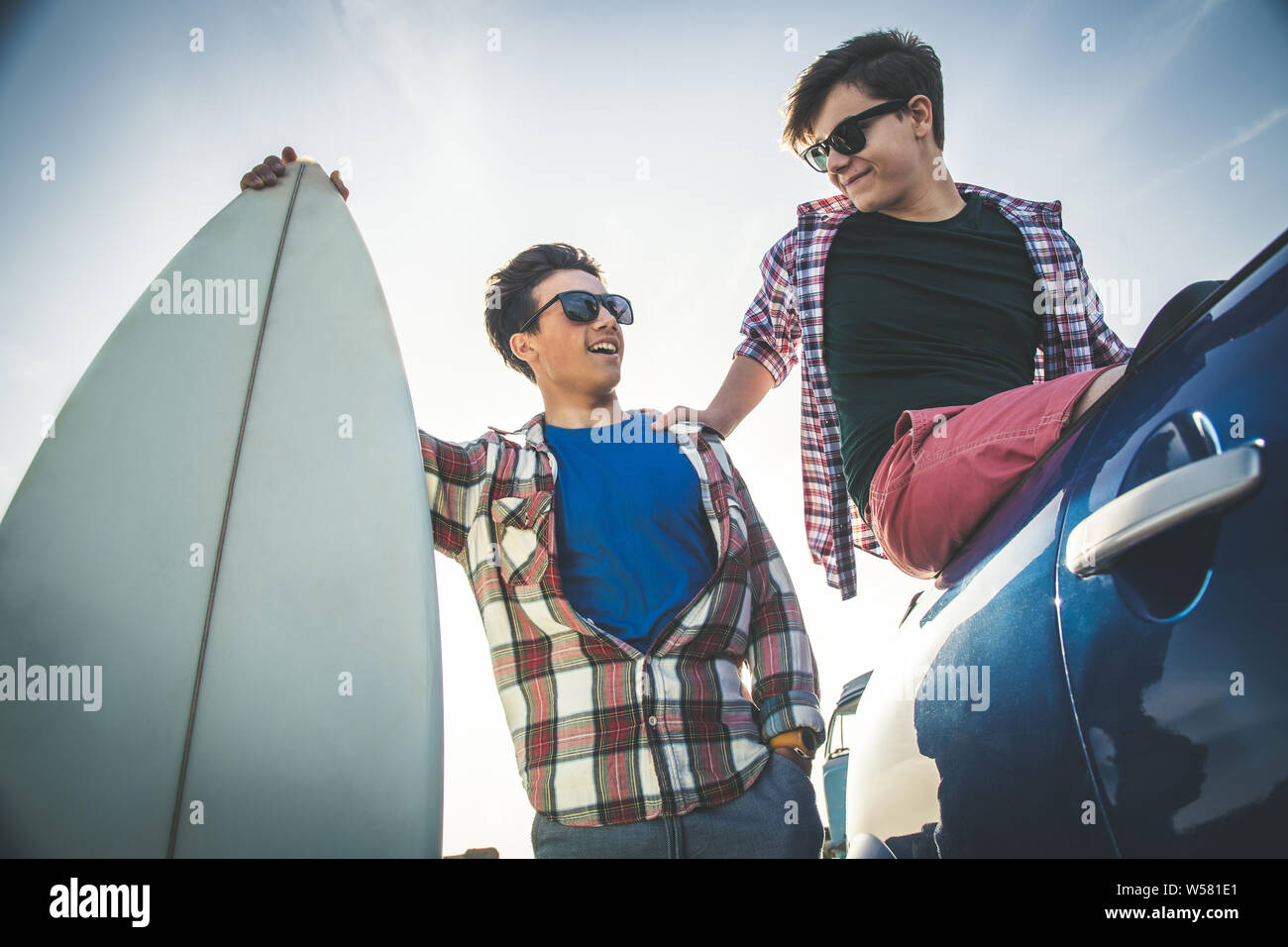 Two young happy teenager best friends laughing with surf board. Closeup ...