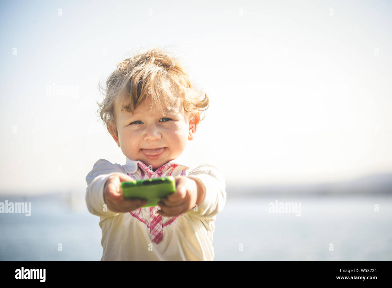 Cute little girl using modern smartphone. Baby holding mobile phone and ...