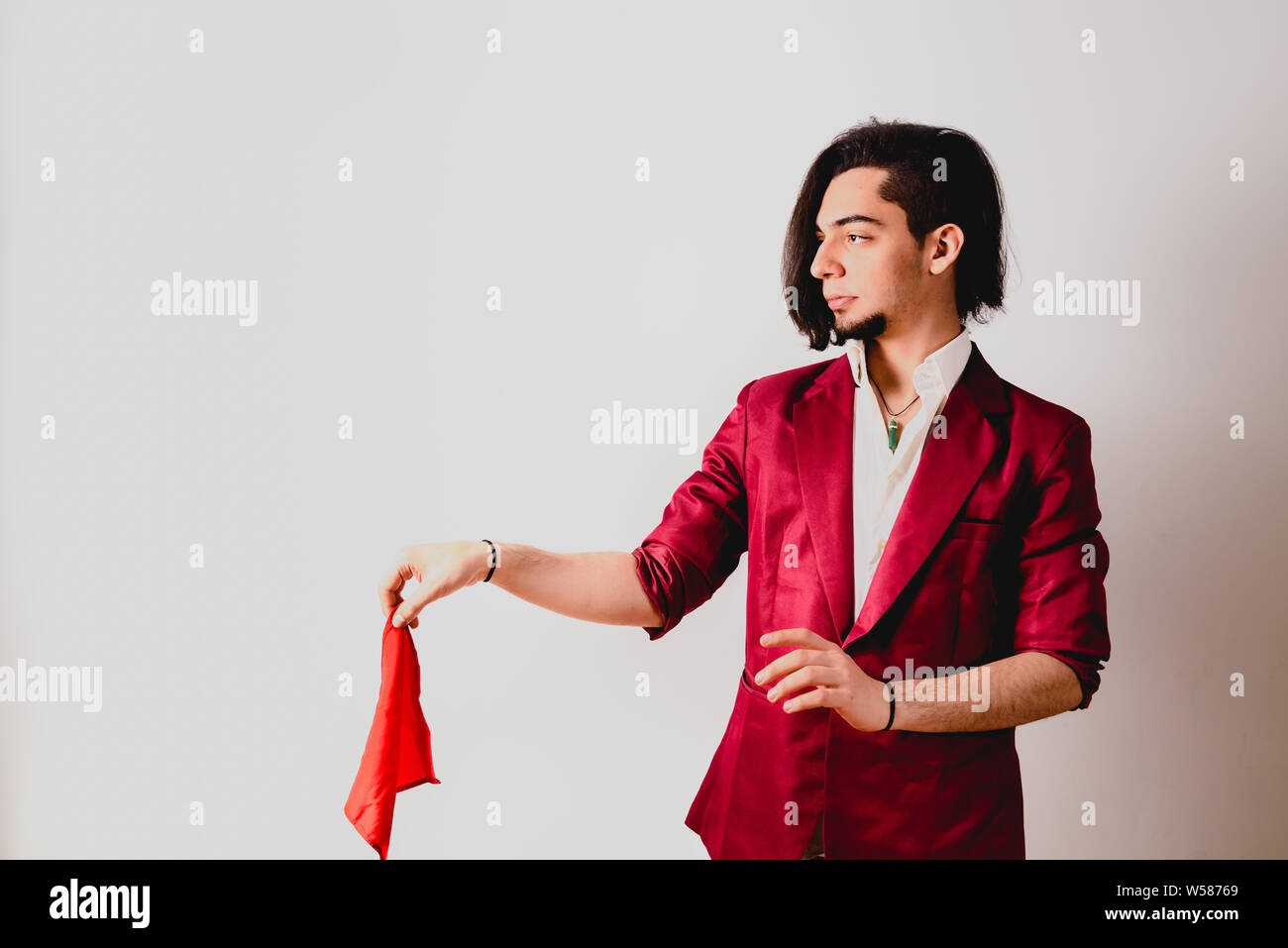 Portrait of young magician handling ropes and bandanas to do magic ...