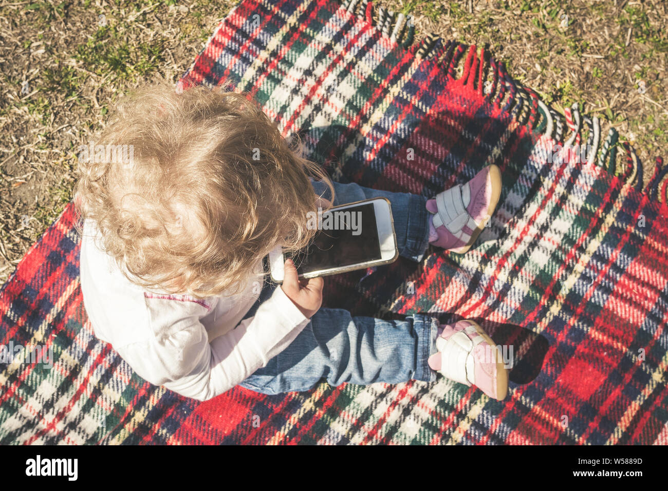 Cute little girl using modern smartphone. Baby holding mobile phone and ...