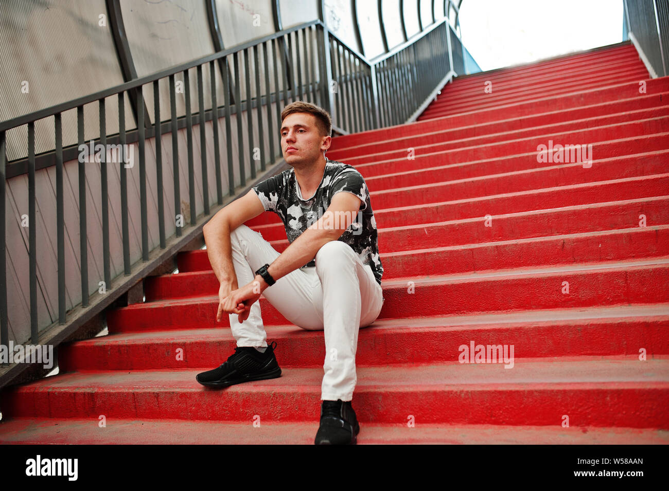 Lifestyle portrait of handsome man posing in red stairs of the city ...