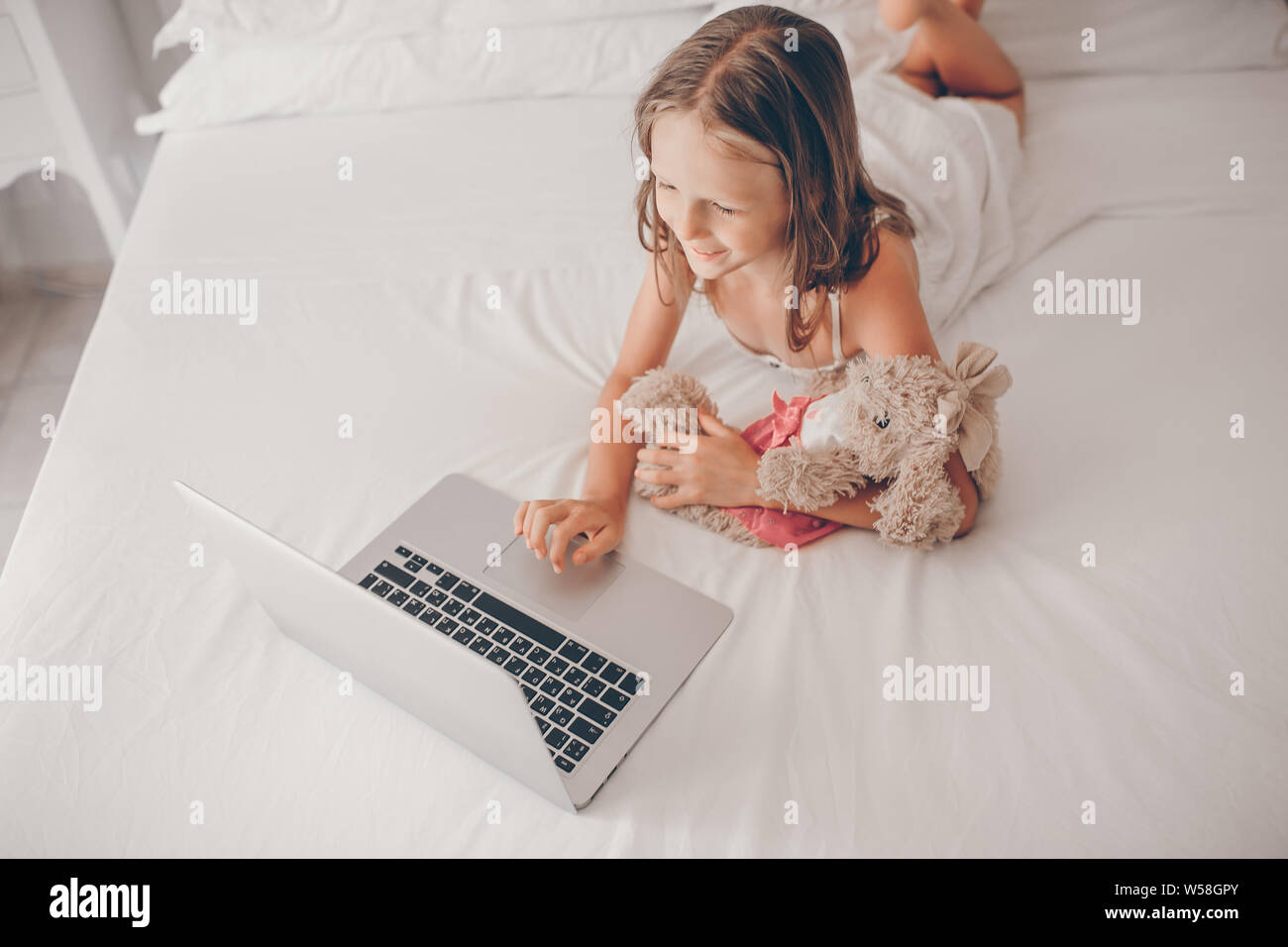 Adorable little kid playing on computer on the bed Stock Photo - Alamy