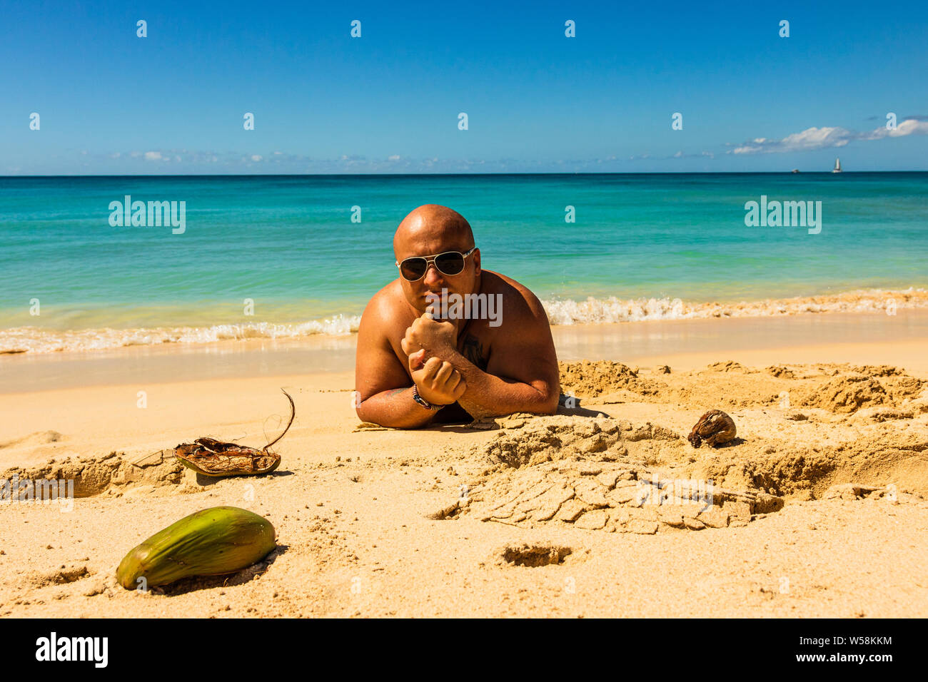 Young man relaxing the sand of Barbados beach. Idyllic afternoon at the ...