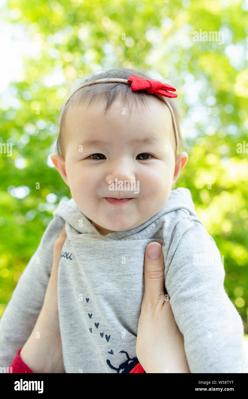 Baby girl wearing small red bow smiles and looks at camera Stock Photo ...