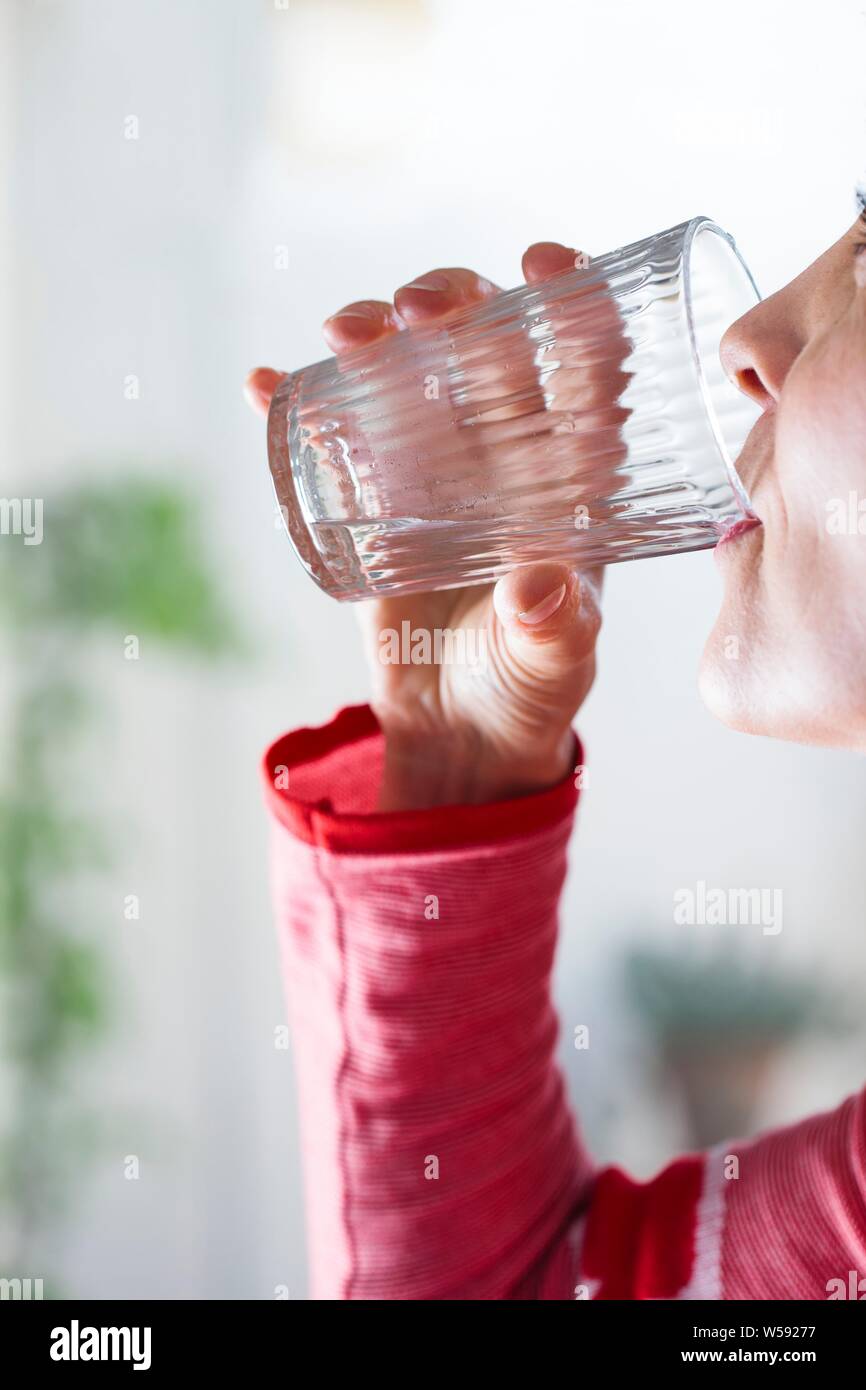 Woman drinking glass of water to hydrate Stock Photo - Alamy