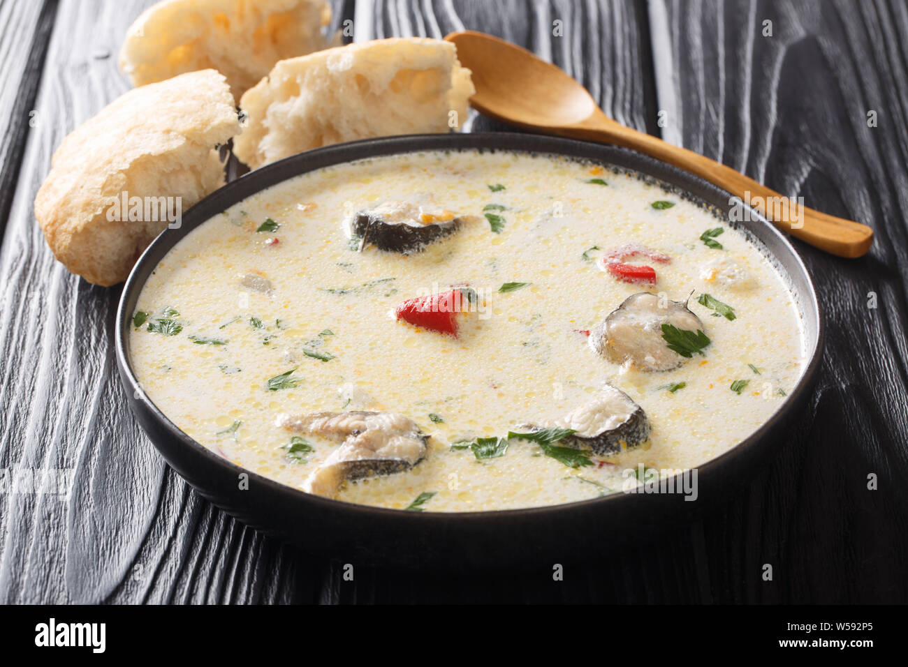 Portion of creamy fish soup with eel, vegetables and herbs close-up in ...