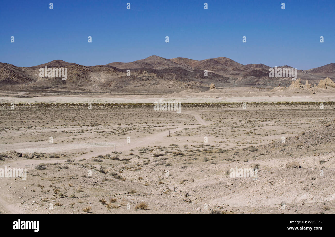Dirt road and trails leading into arid valley. Barren desert valley ...