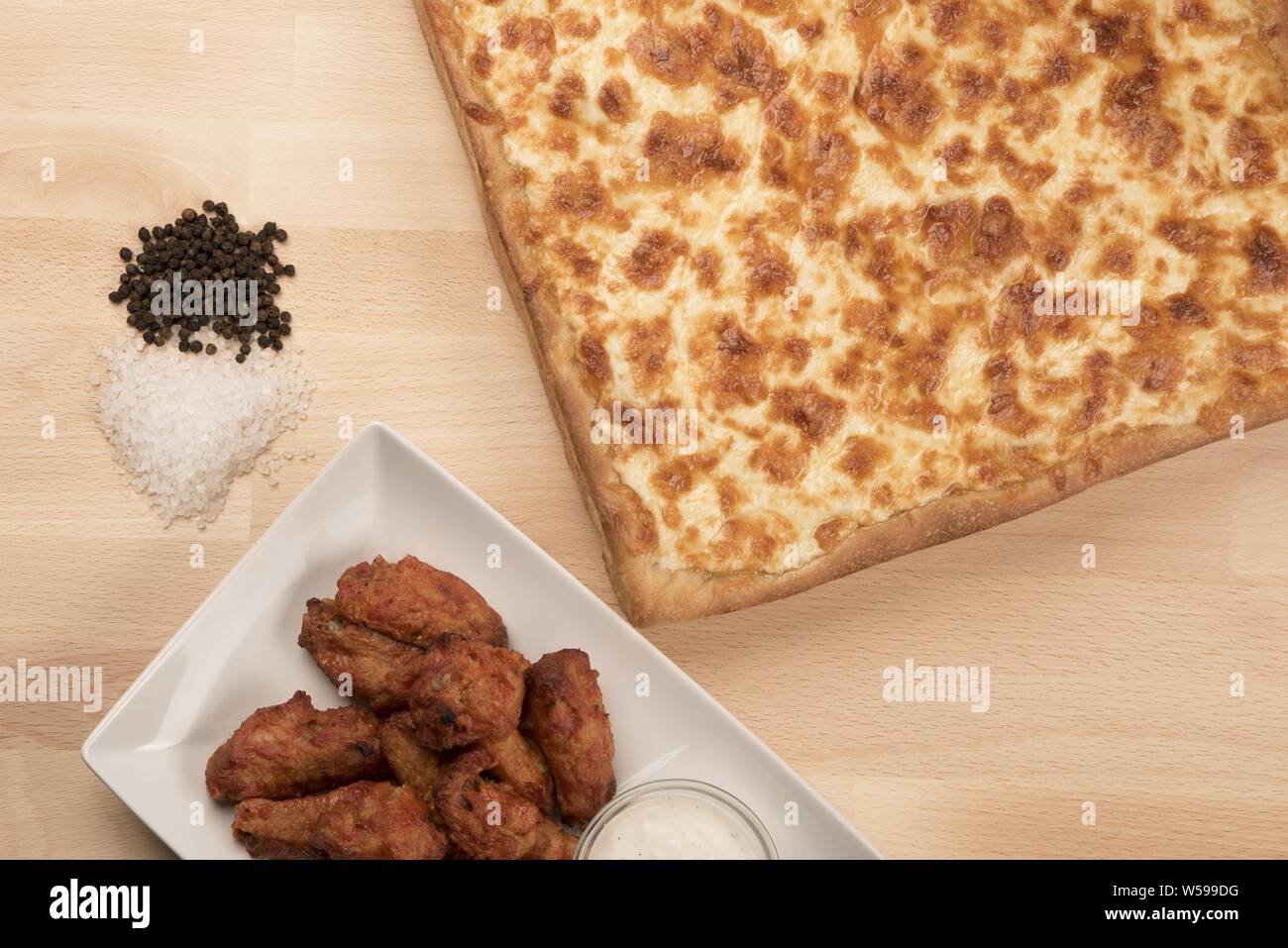Overhead shot of chicken wings in a bowl with a square-shaped cheese ...