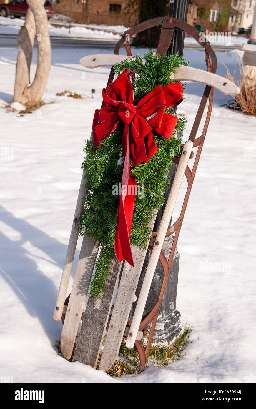 Christmas pine bough with bright red bow on retro wooden sled in snow ...