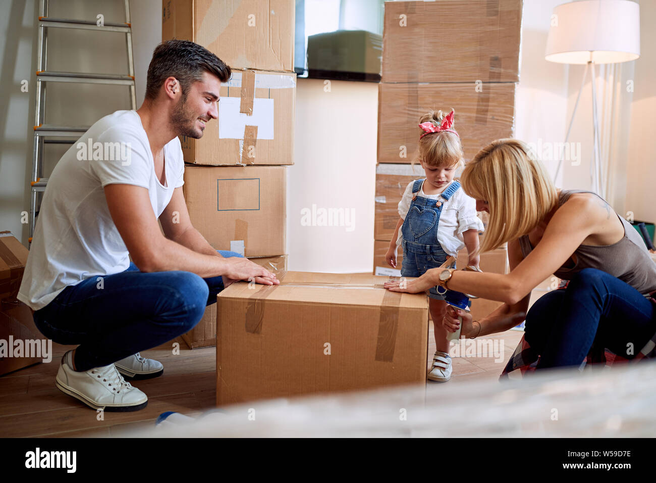 Happy Family unpacking boxes in new home Stock Photo - Alamy