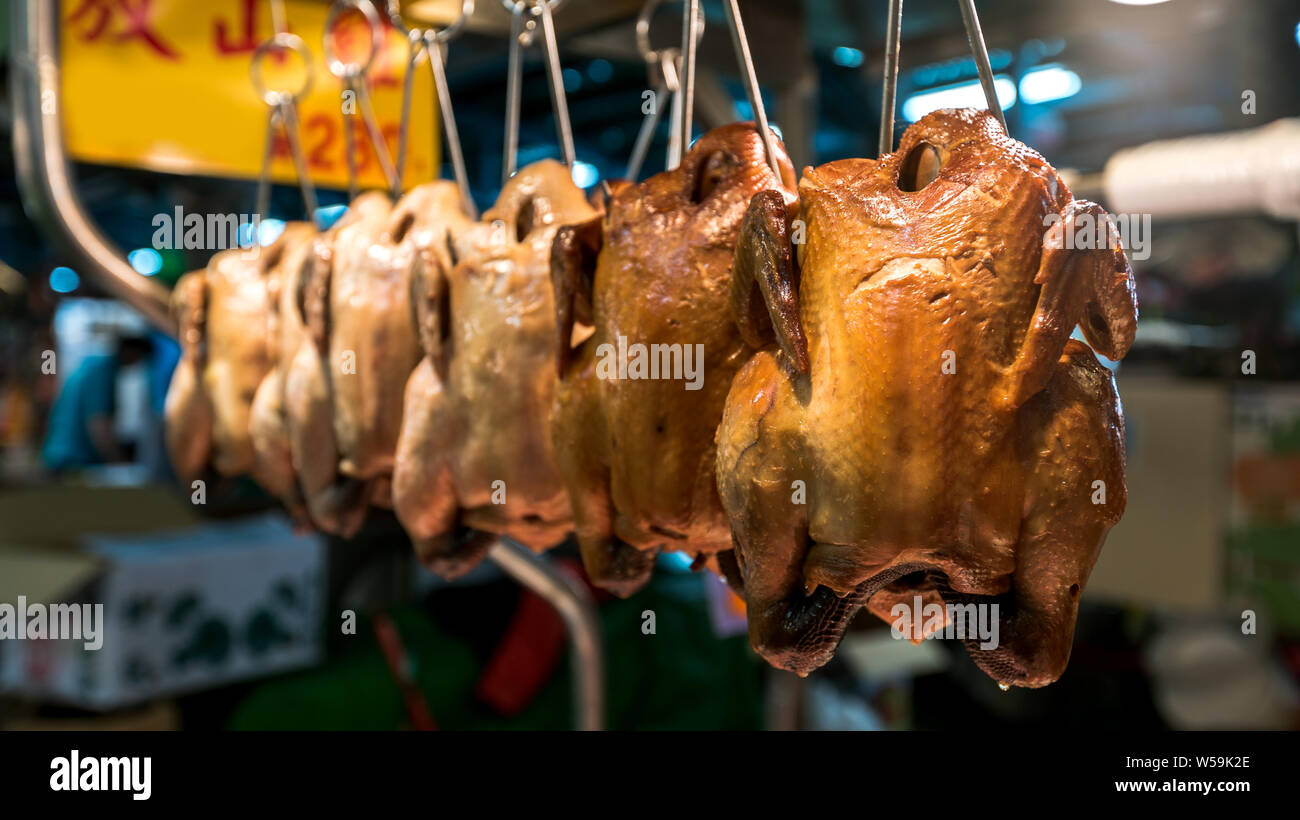 Close-up view of a stall vendor with chicken meat hanging in ...
