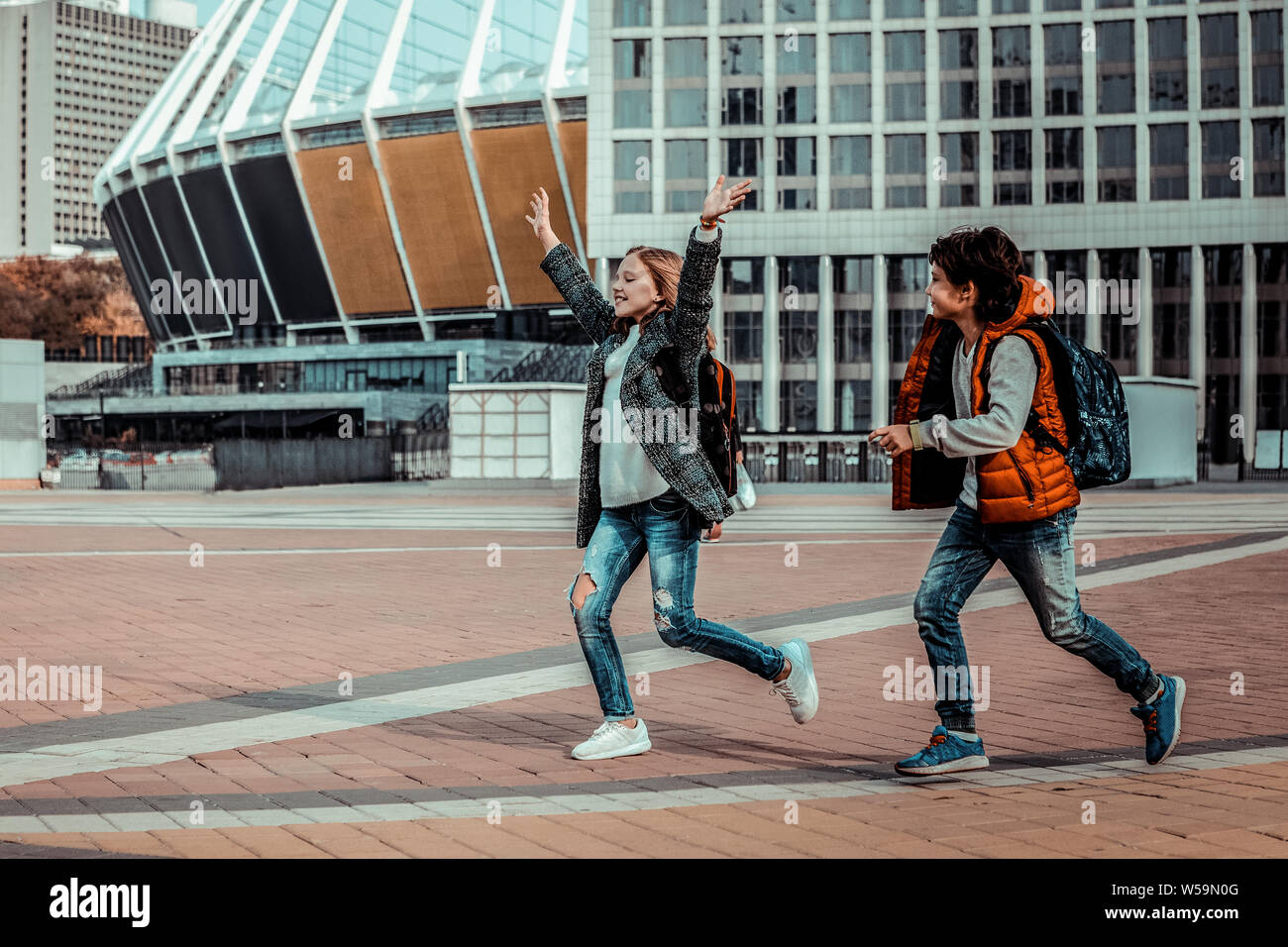 Time to walk. Cute little female raising arms while running home after ...