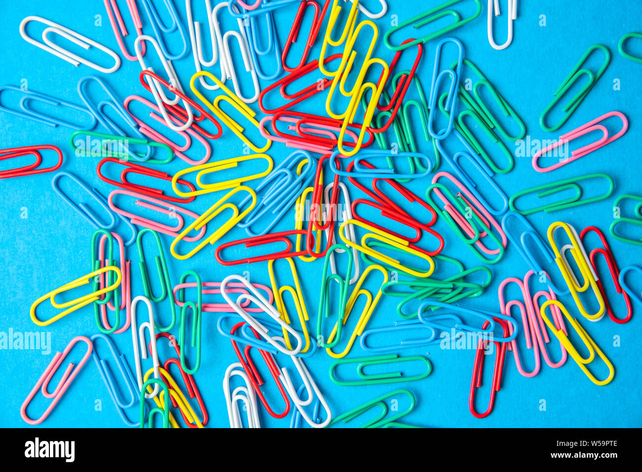 multi-colored paper clips on a blue background Stock Photo - Alamy