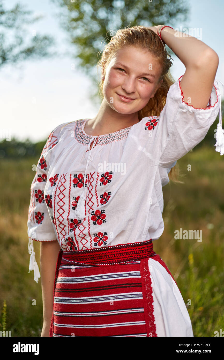 Portrait of a Romanian girl in traditional costume in an oak forest ...