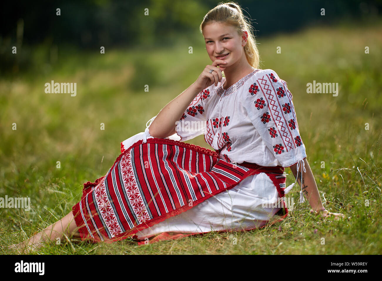Portrait of a Romanian girl in traditional costume in an oak forest ...