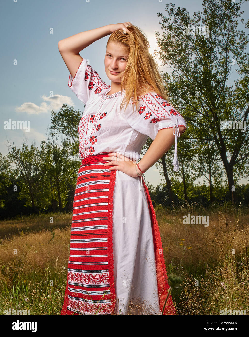 Portrait of a Romanian girl in traditional costume in an oak forest ...