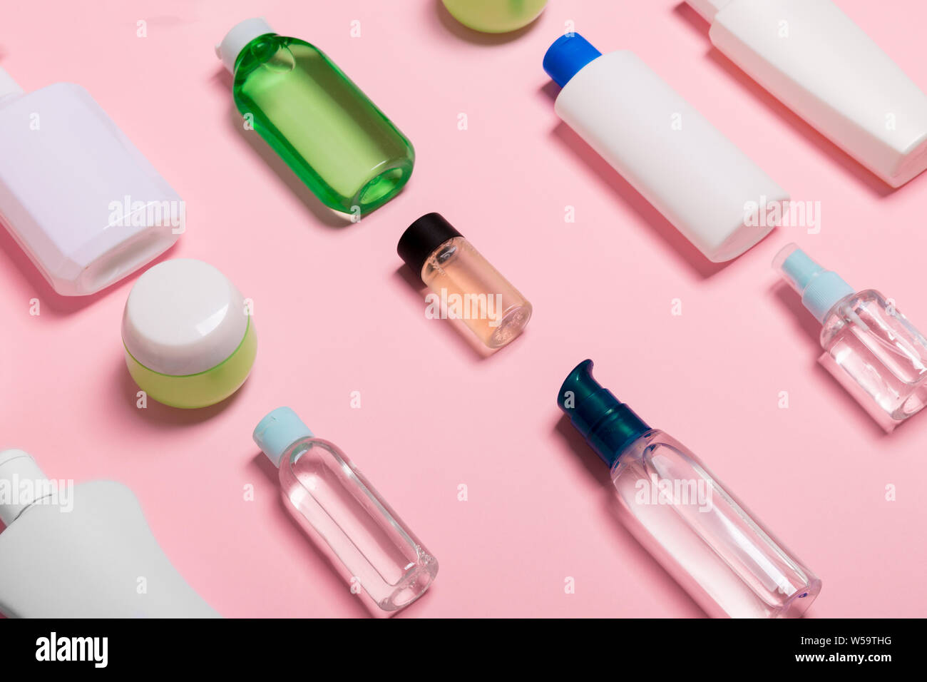 Top view of cosmetic containers, sprays, jars and bottles on pink ...