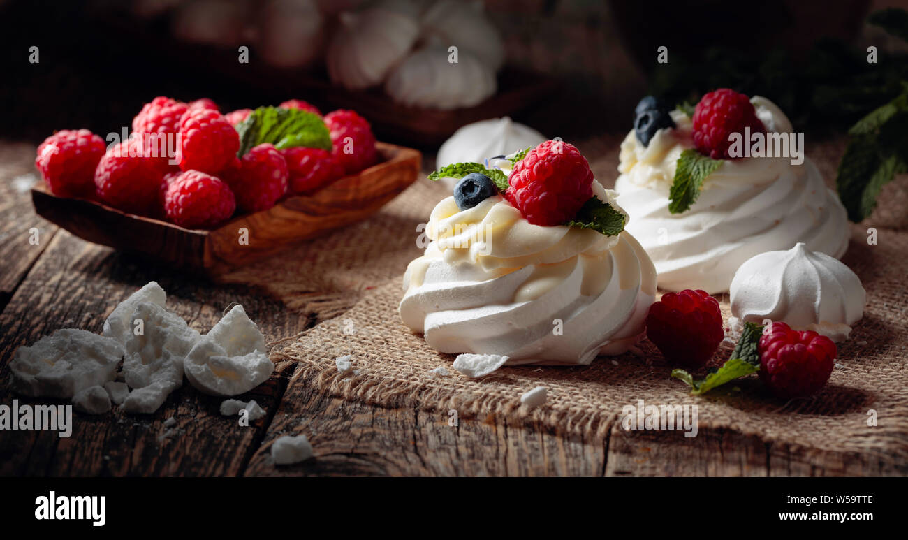 Dessert Pavlova with raspberries, blueberries and mint on a old wooden ...