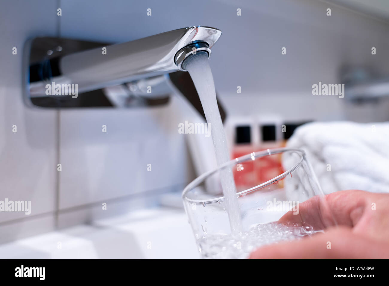 Faucet with flowing water, hand and drinking glass Stock Photo - Alamy