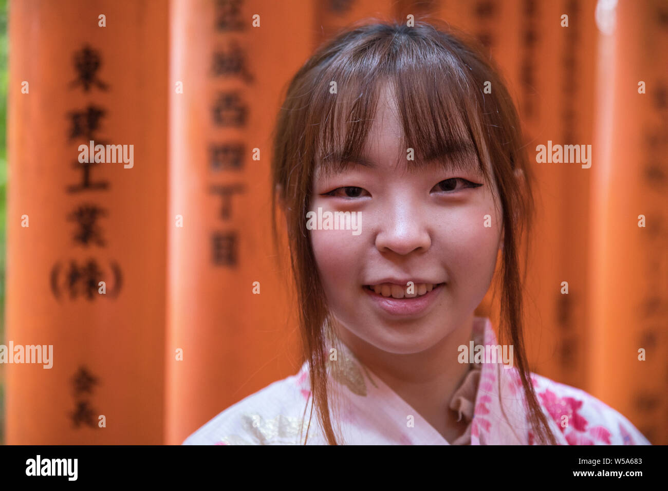 A young woman stands amongst the torii gates at the Fushimi Inari ...
