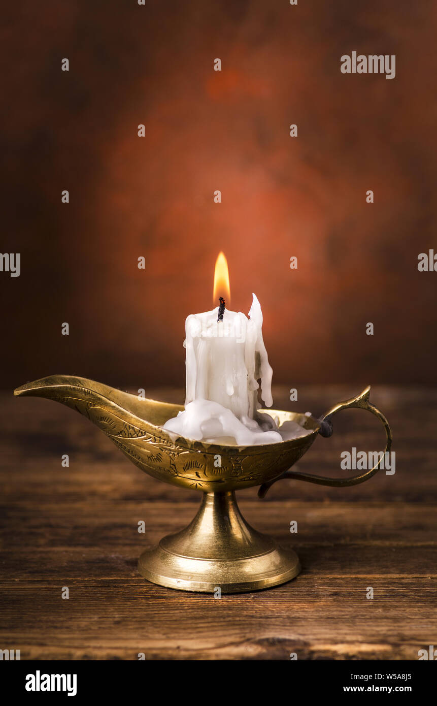 still life.A warm light coming from the flame of a candle in the brass ...
