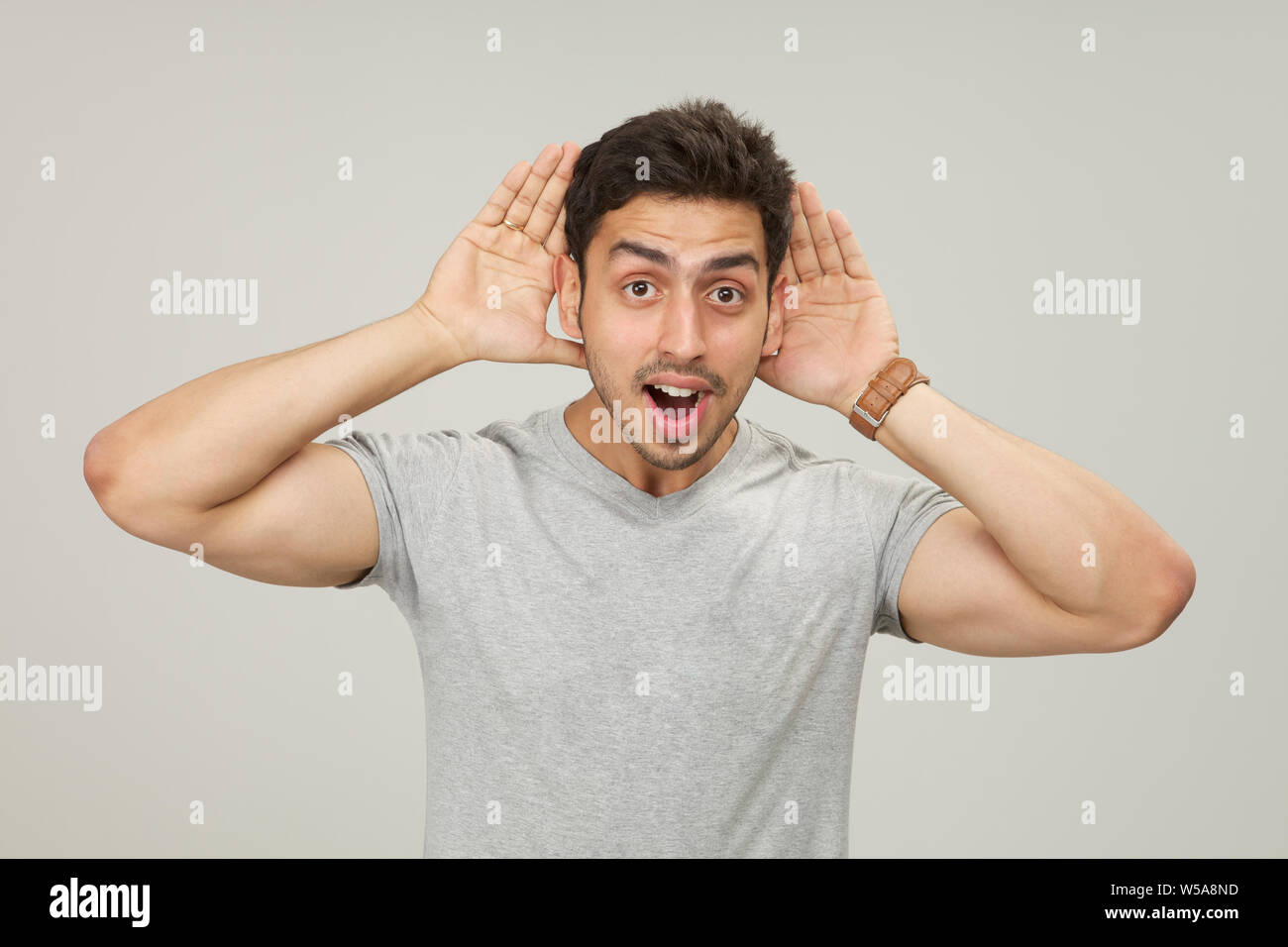Portrait of a man cupping hands to ears Stock Photo - Alamy