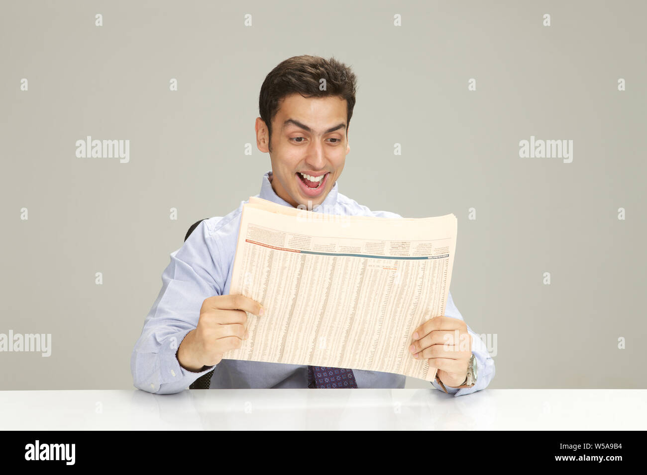 Businessman reading a newspaper and smiling Stock Photo - Alamy
