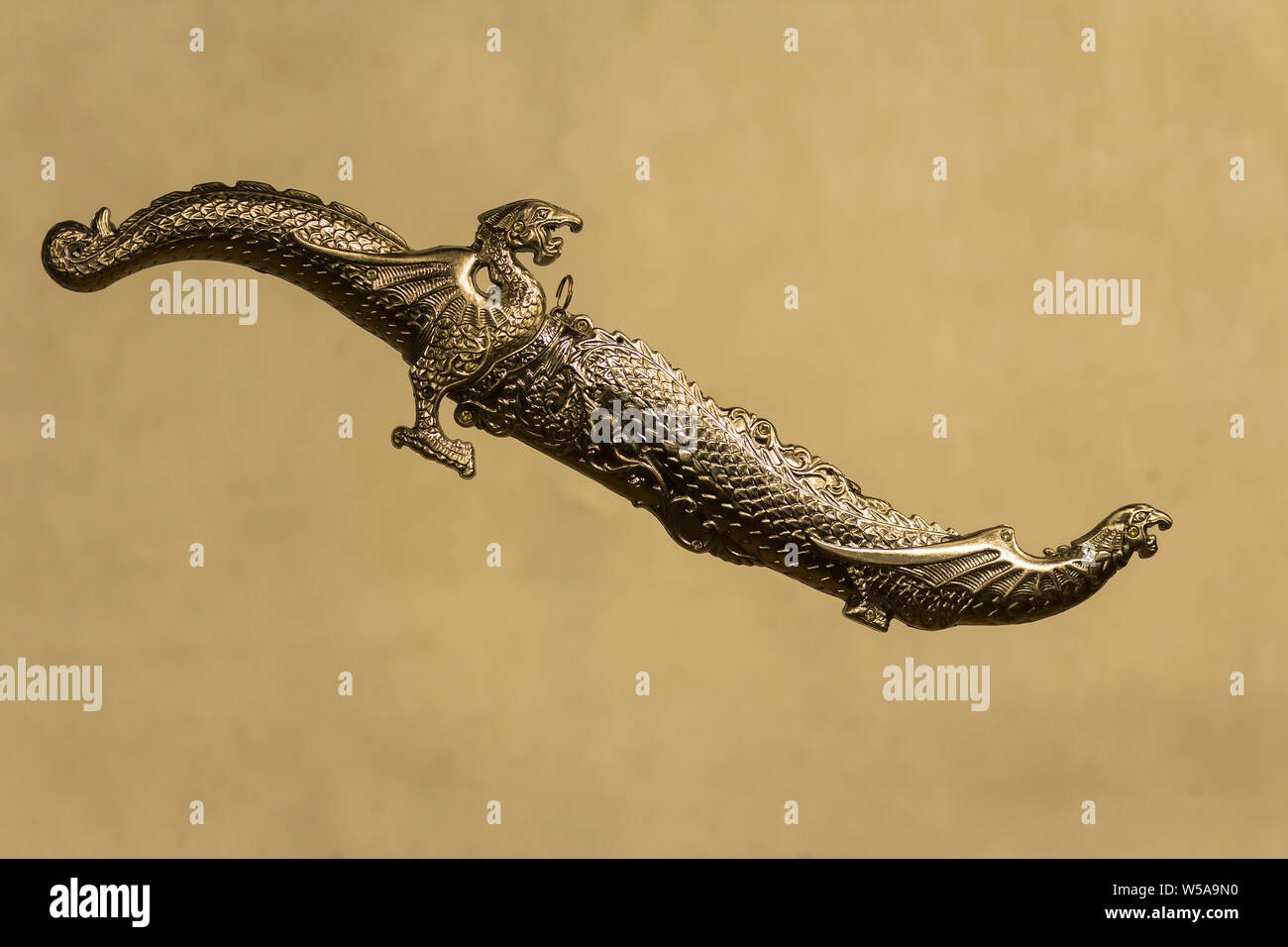 decorative carved dagger with heads of dragons in a sheath on a gray ...
