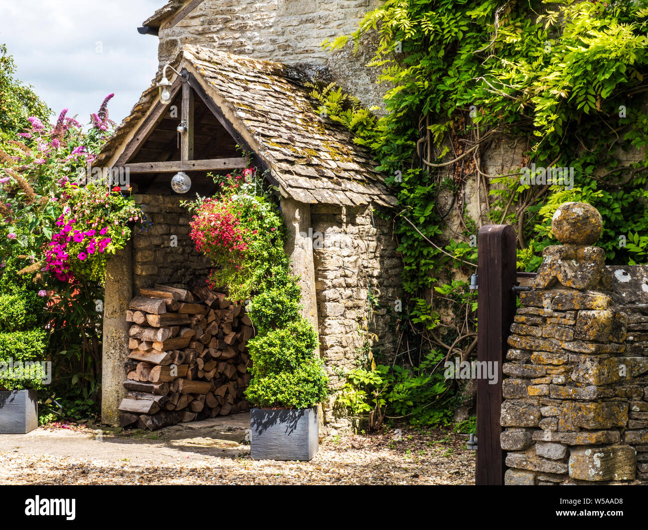 A pretty porch used as a log store on a stone cottage in the Cotswolds ...