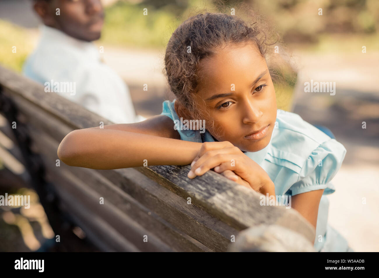 Thoughtful little female leaning on the bench Stock Photo - Alamy