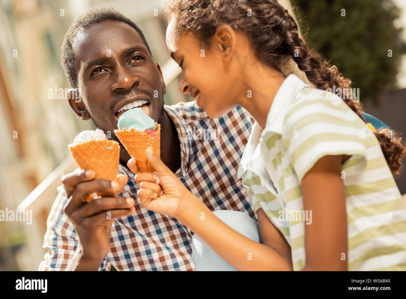 Charming little female feeding her daddy with ice-cream Stock Photo - Alamy