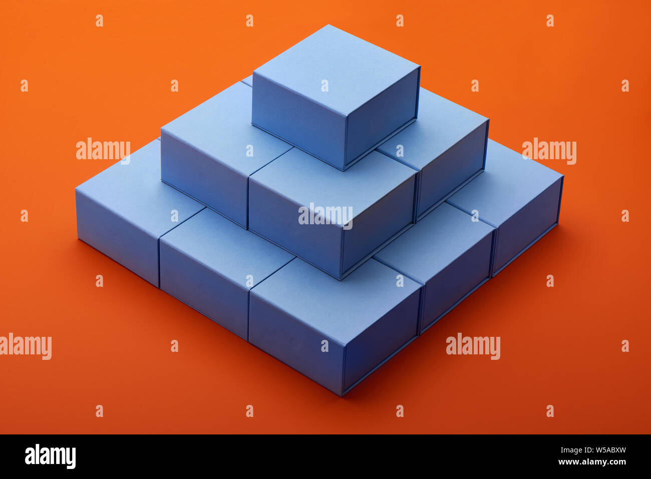 Pyramid of light blue gift boxes on bright orange paper background ...