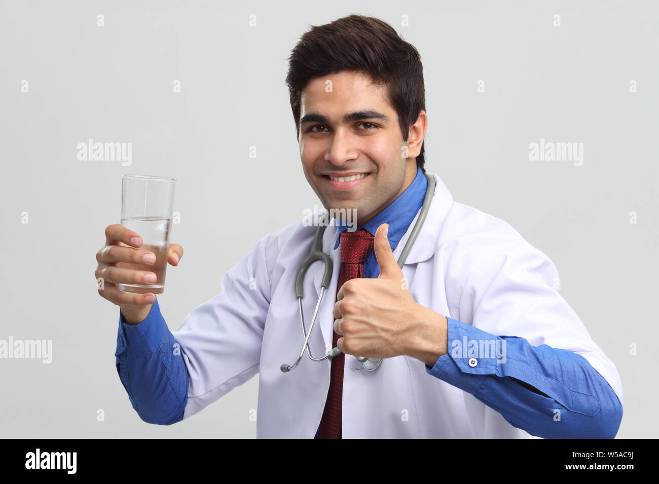 Male doctor holding a glass of water and showing thumbs up sign Stock ...