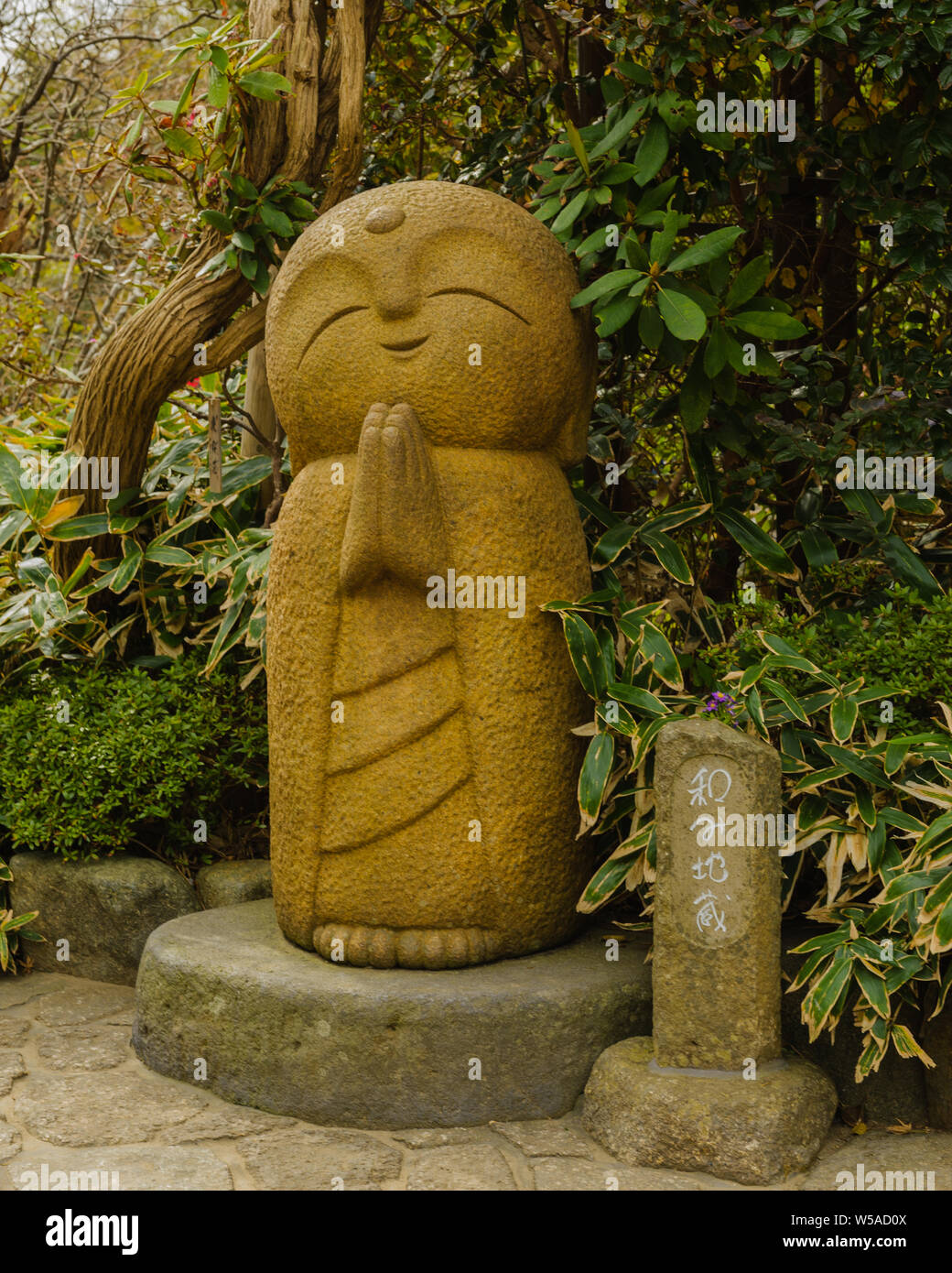 Little stone statue of a small praying monk in a funny looking shape ...