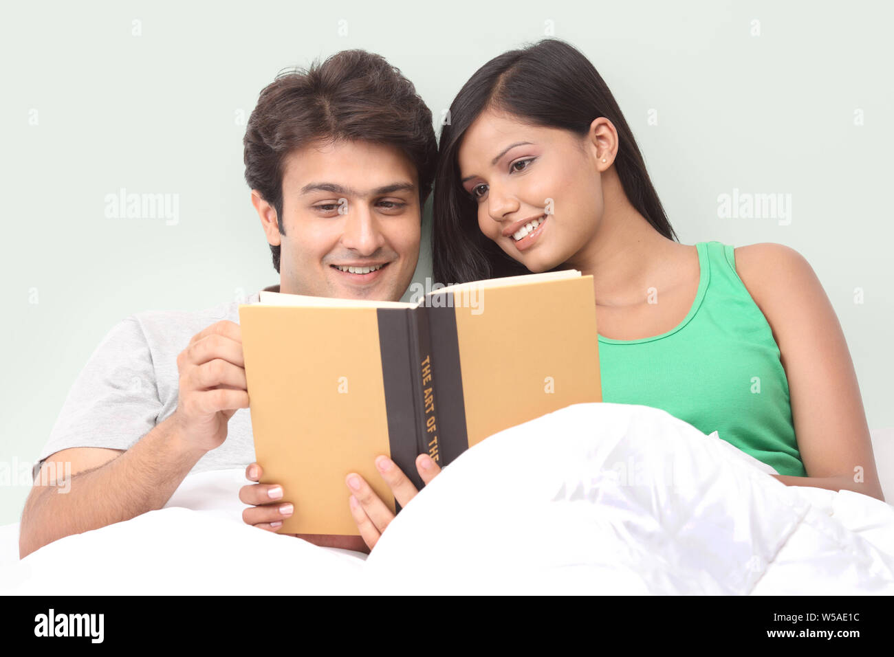 Couple reading a book and smiling Stock Photo - Alamy