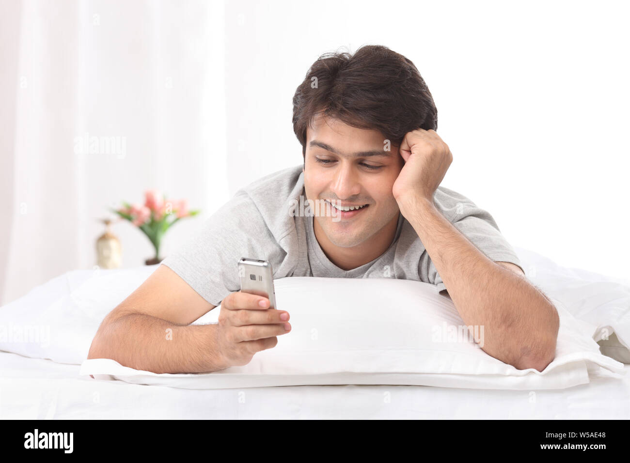 Man lying on bed and text messaging Stock Photo - Alamy