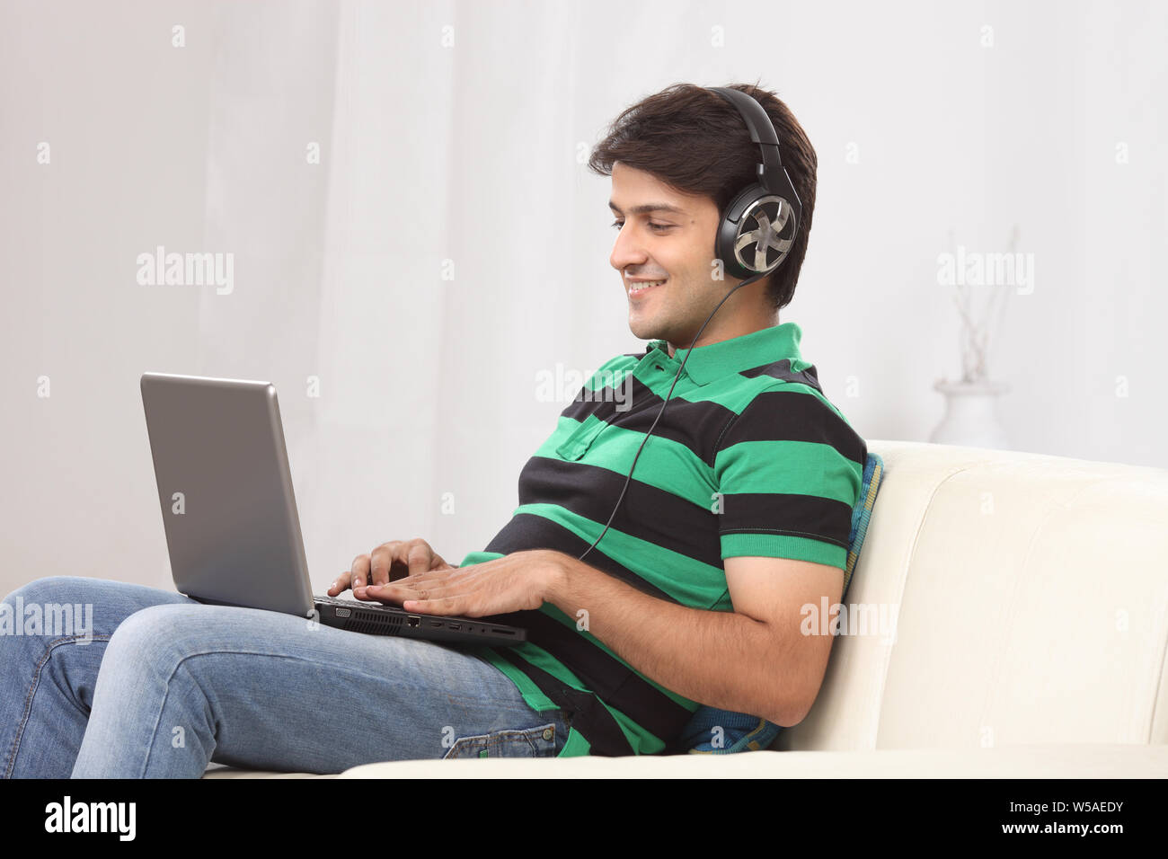Man wearing headphones and using a laptop Stock Photo - Alamy