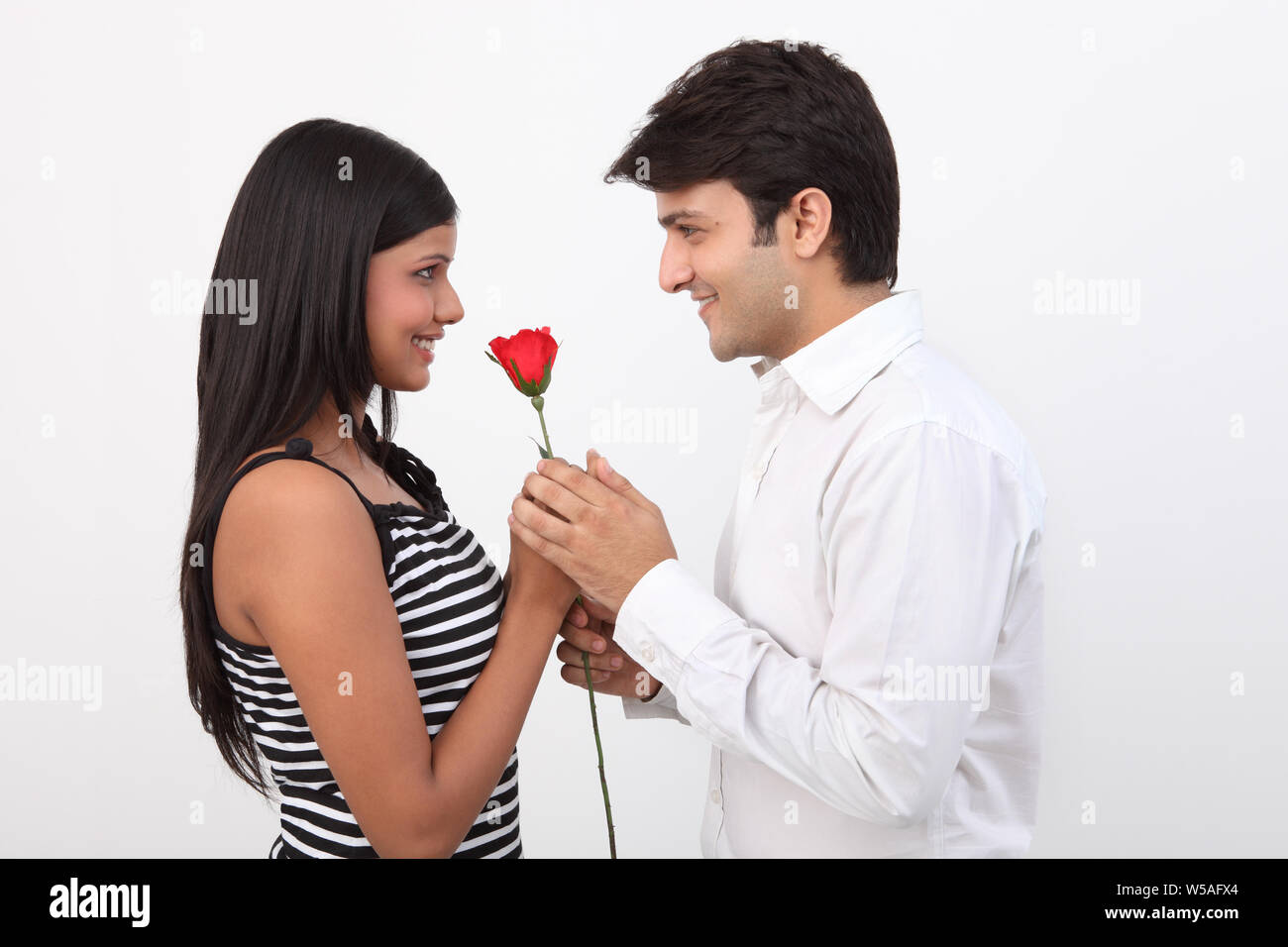 Man offering a rose to woman and smiling Stock Photo - Alamy