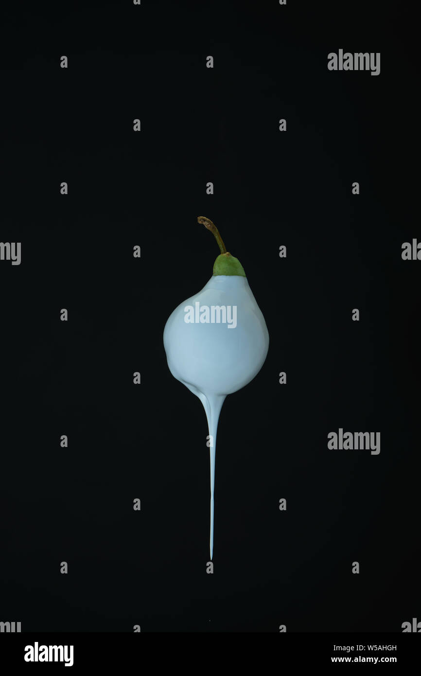 Beautiful fresh pear dripping white paint on a black background ...