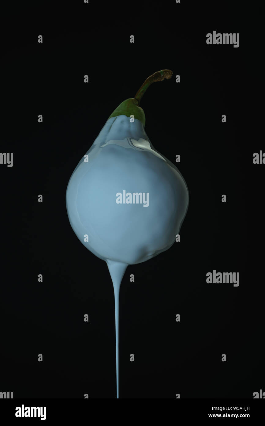 Beautiful fresh pear dripping white paint on a black background ...