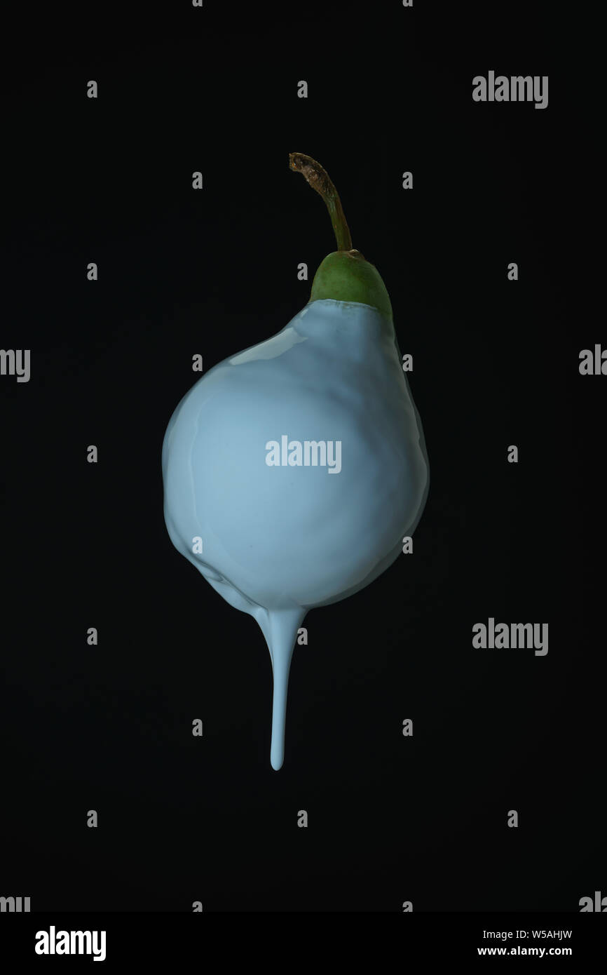Beautiful fresh pear dripping white paint on a black background ...