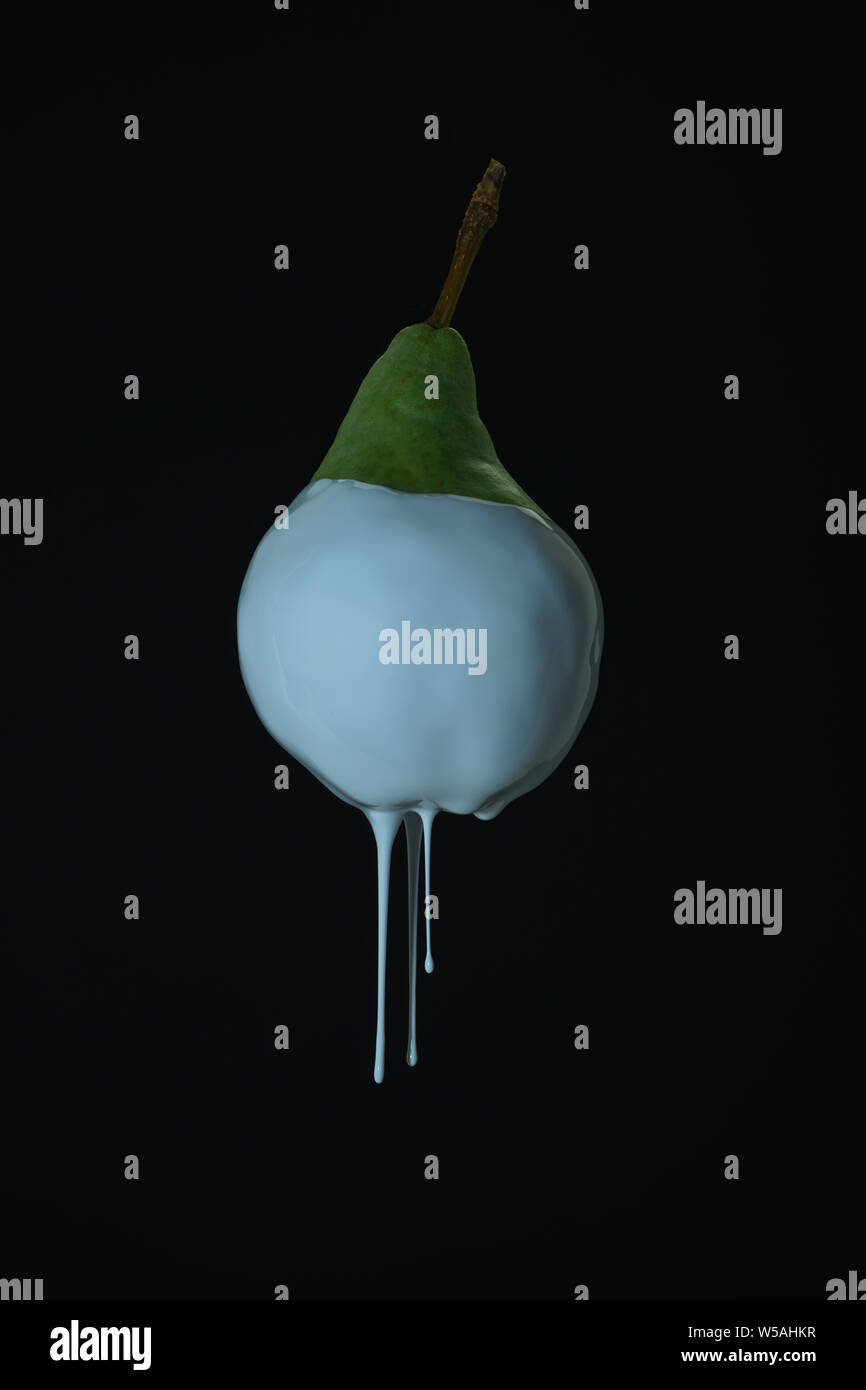 Beautiful fresh pear dripping white paint on a black background ...