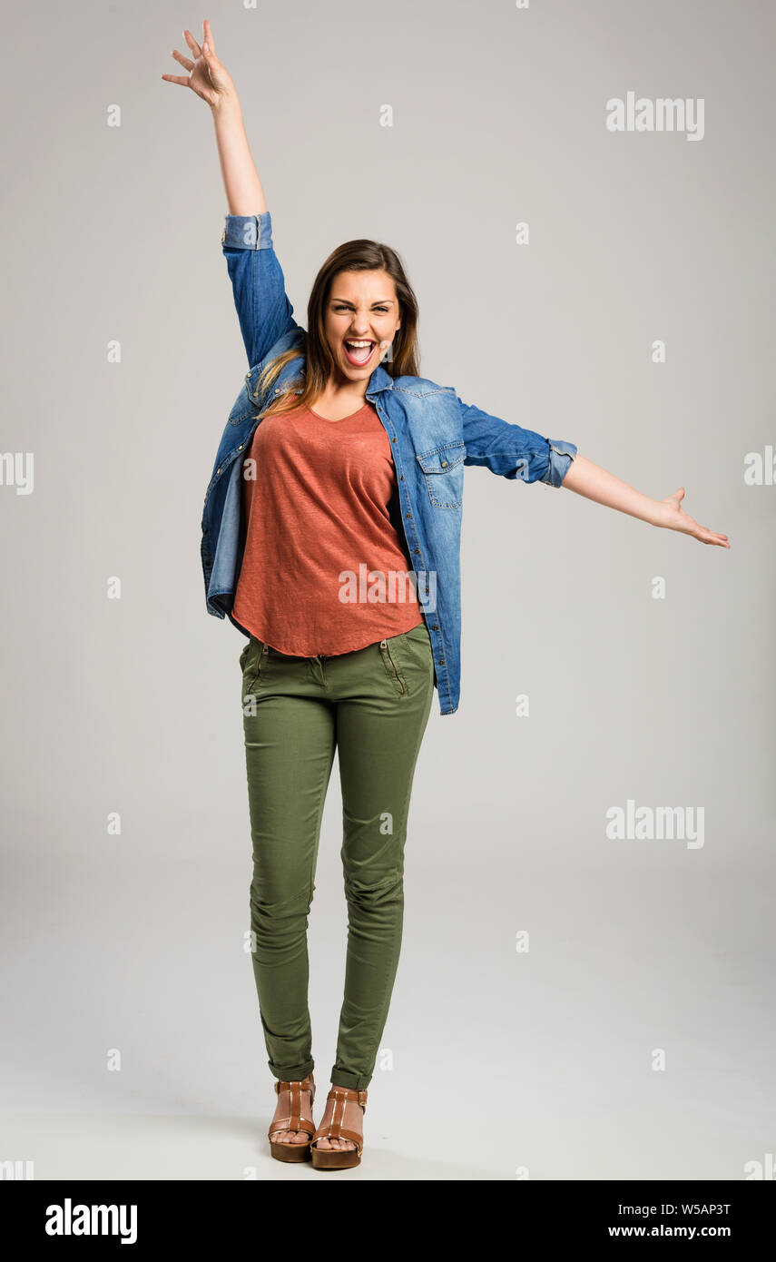 Beautiful happy woman with arms up over a gray background Stock Photo ...