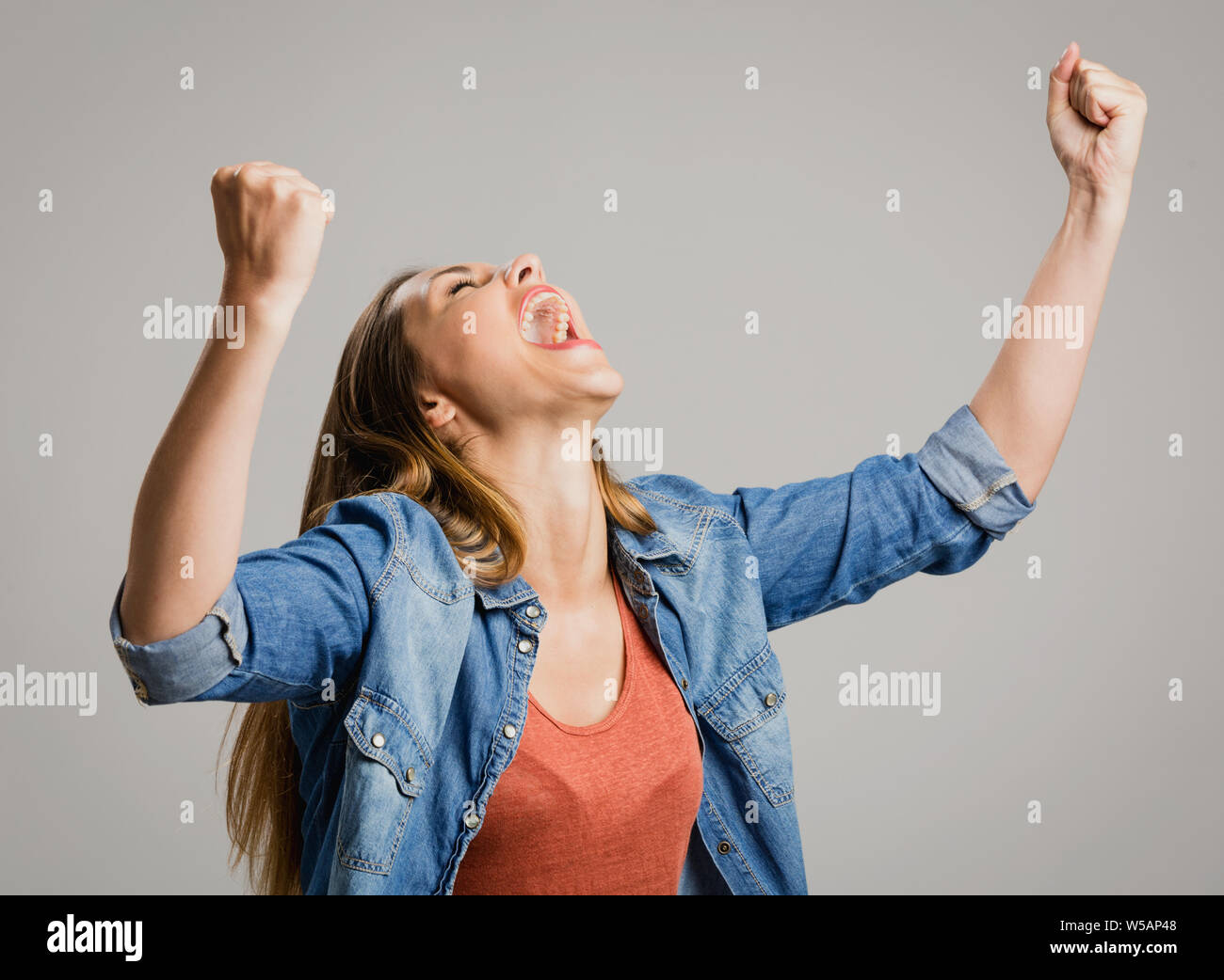 Beautiful happy woman with arms up over a gray background Stock Photo ...