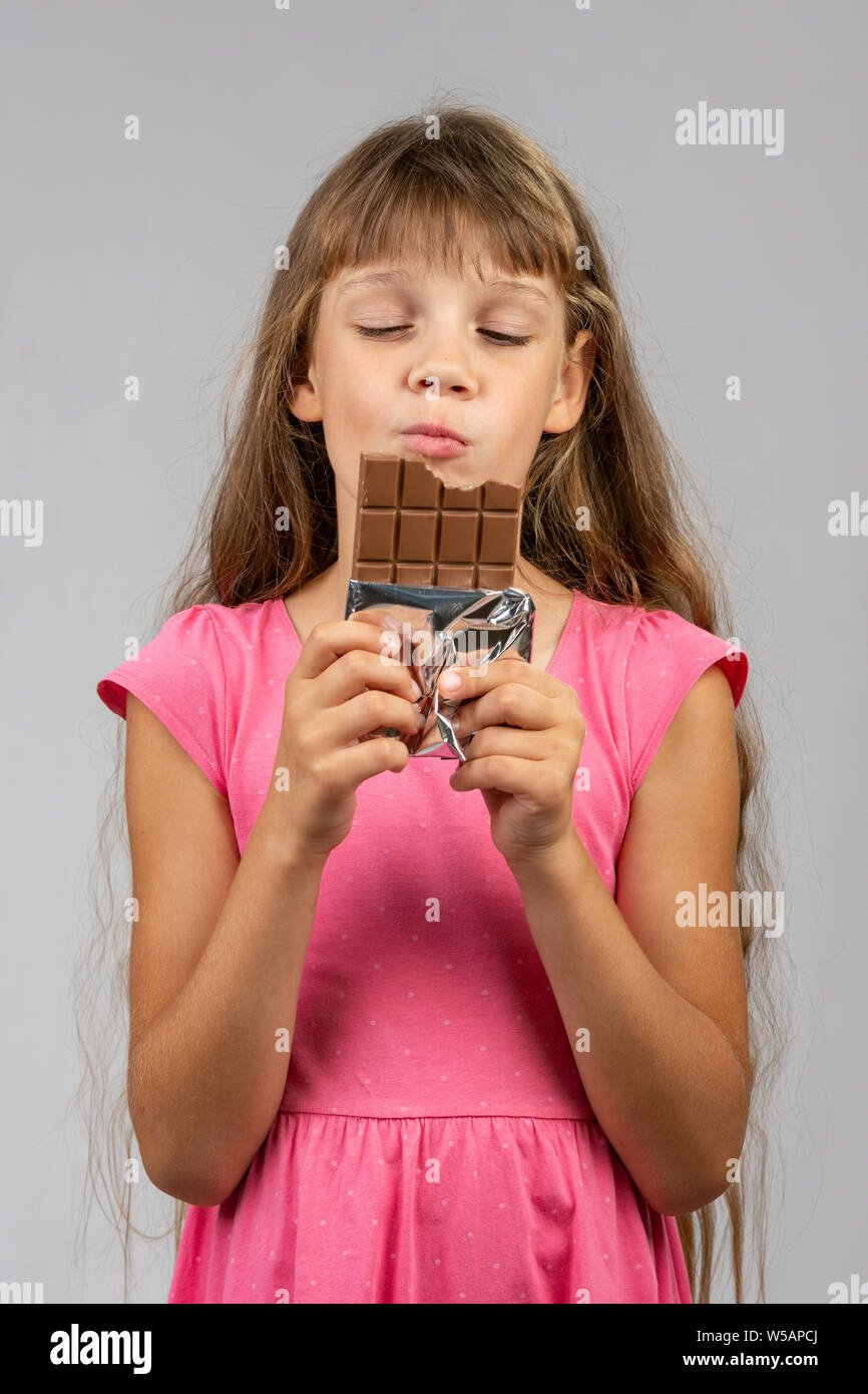 Eight-year-old girl with pleasure eats chocolate bar Stock Photo - Alamy