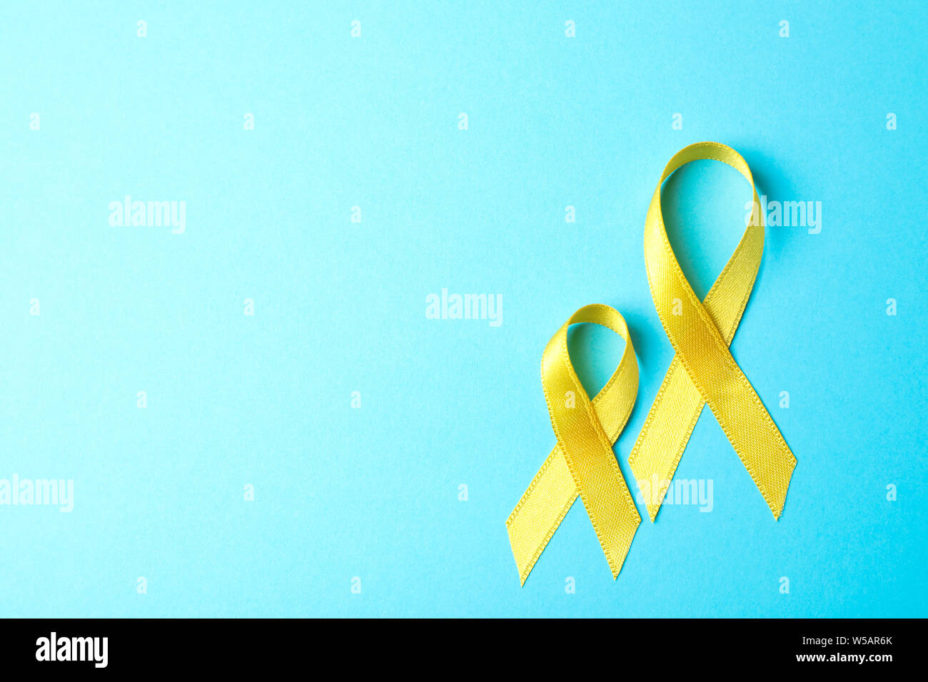 Yellow awareness ribbons on blue background, space for text Stock Photo ...