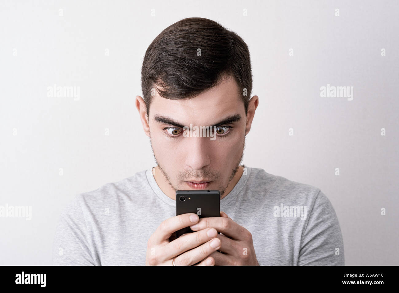 Funny portrait of man with a smartphone in his hands looking at the ...