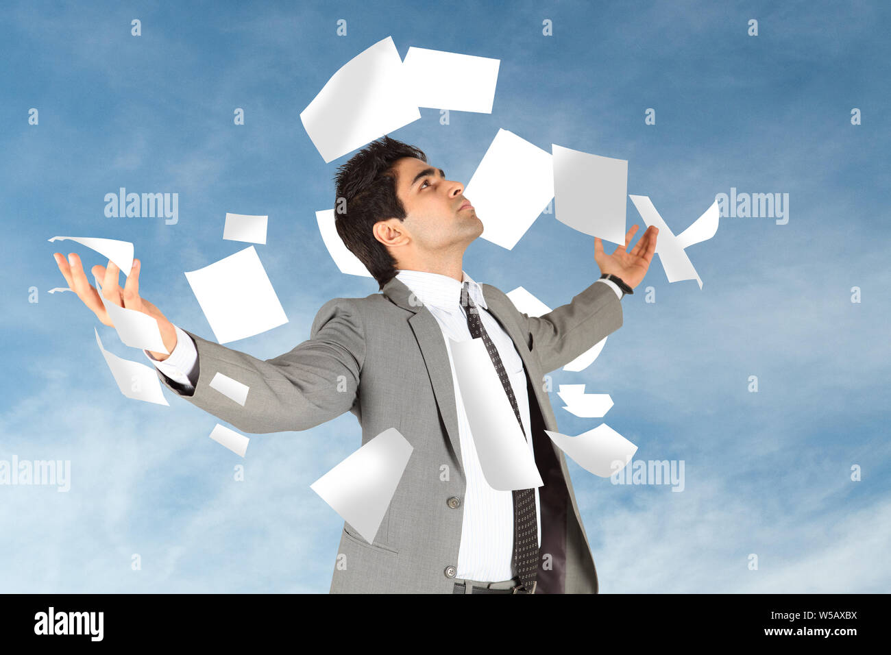 Papers falling on a businessman standing with his arms outstretched ...